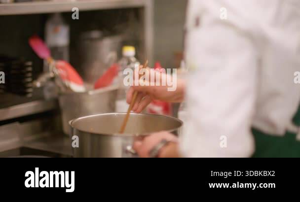 Professional kitchen. Stirring food. Chef in white uniform mixing hot ...