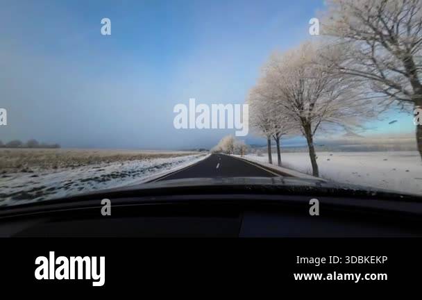 A winter road from a car window. Asphalt road and frosted trees under a ...
