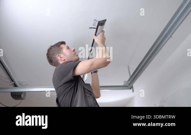Man in workwear connecting electrical wires while installing ceiling ...