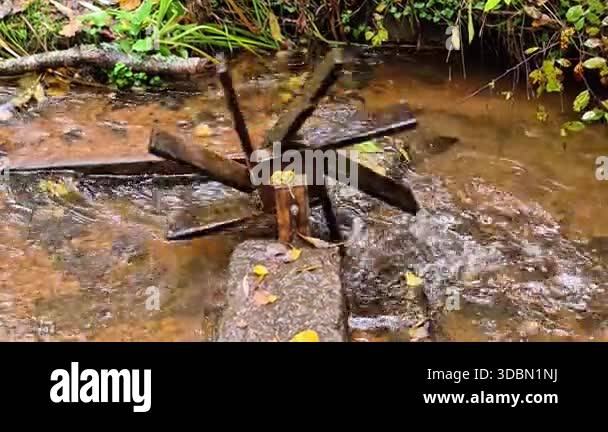rustic wooden wheel turning in creek, mossy paddles slowly rotate in ...