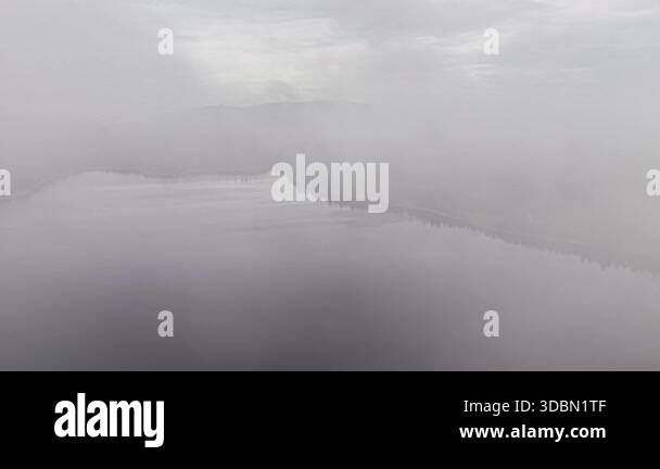 silent grey fog enveloping hidden lake with muted tones, aerial ...