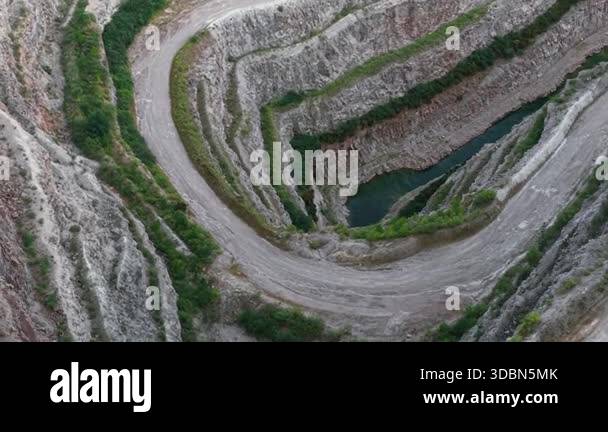 Mining road looping tightly around flooded trench carved into terraced ...