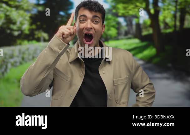 Man lifts finger while pointing across a sunlit park scene featuring ...