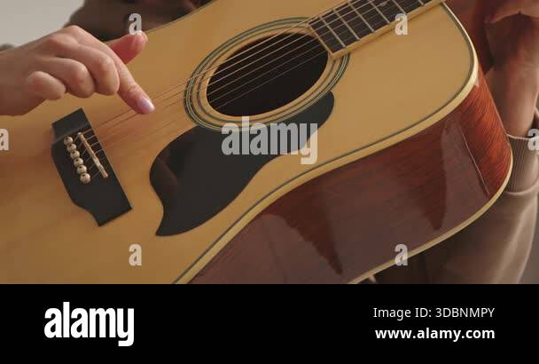 A person strumming the strings of an acoustic guitar, focusing on the ...