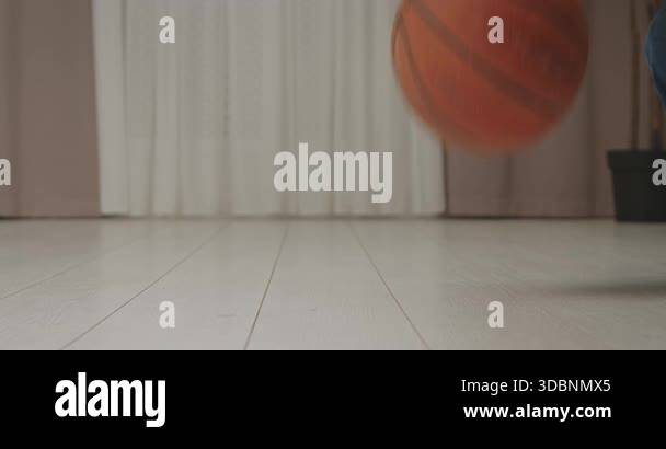 Close up of a basketball in motion, bouncing off a light wooden floor ...