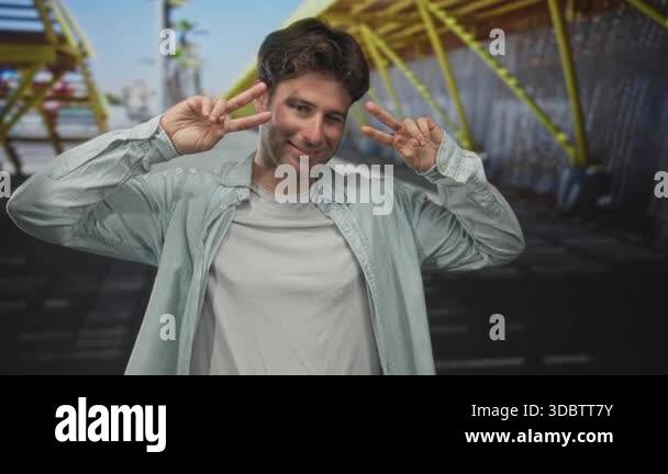 Man showing double peace signs with hands near face on street under ...