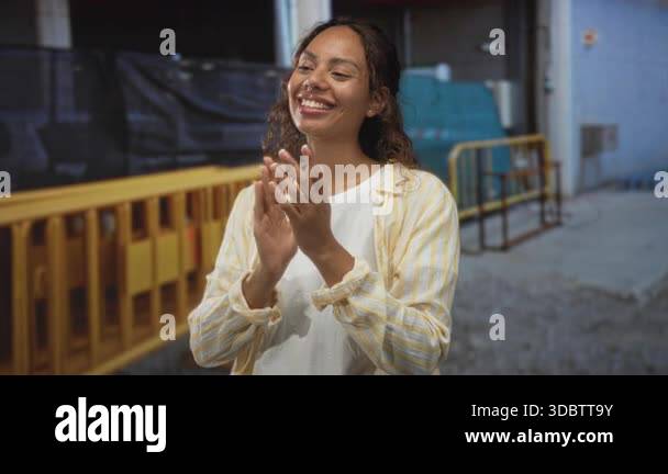 Woman clapping hands by a yellow safety barrier at a building ...