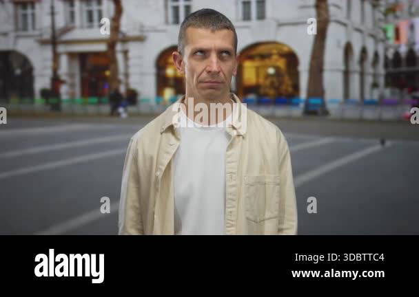Man standing on a busy outdoor city street, wearing a casual shirt ...