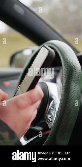 The driver, while driving a car, uses a mobile phone, types text in a ...