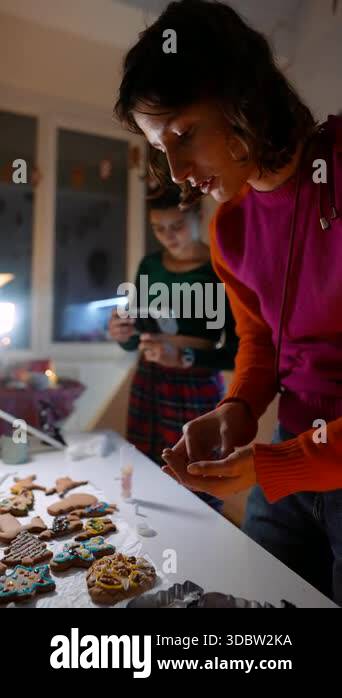 woman filming cookie decorating session smartphone tripod closeup hands step instruction social ...