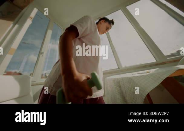 sideangle person performing light weight reps near large window, casual ...
