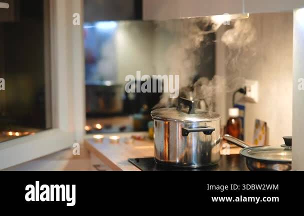 steaming pot on stove in ambient kitchen, metal saucepan with lid ...