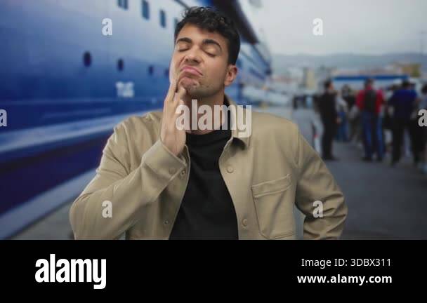 Man props chin then leans on ship at port while hispanic male tourist ...