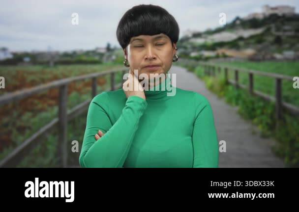 Woman expressing emotions in a green top in a peaceful park setting ...
