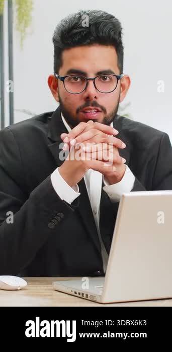 Indian young businessman working on laptop computer shakes finger and ...