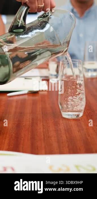 A person pours refreshing water into a glass during a professional ...