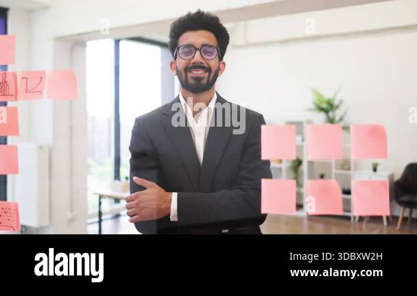 An Indian businessman smiles while making an okay gesture, working on a ...