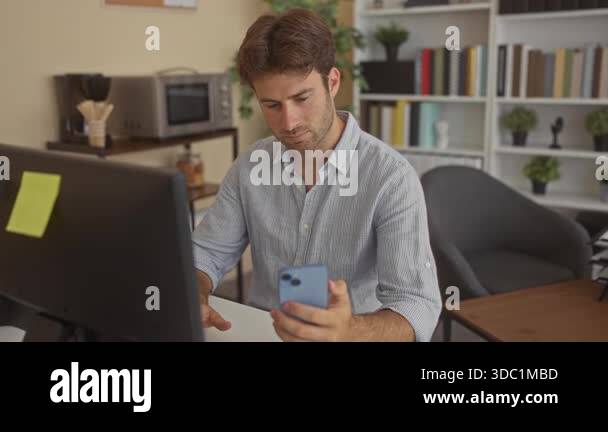 Man holding smartphone and typing on keyboard at desk using desktop ...