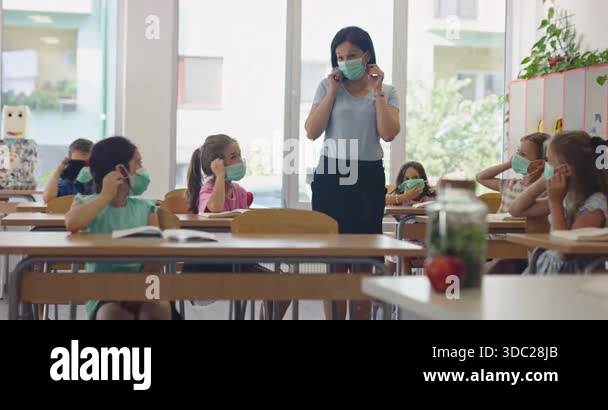 Female teacher wearing a protective face mask demonstrating hand ...