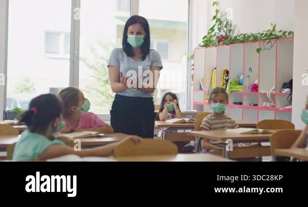 Female teacher wearing a protective face mask demonstrating hand ...