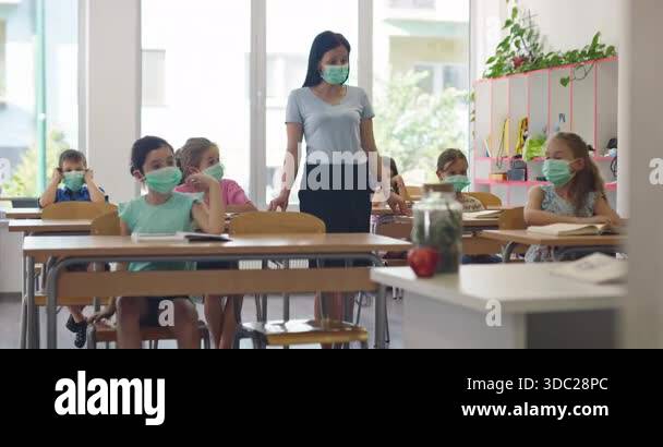Female teacher wearing a protective face mask demonstrating hand ...