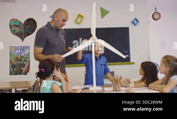 Elementary school teacher explaining wind turbine model to curious ...