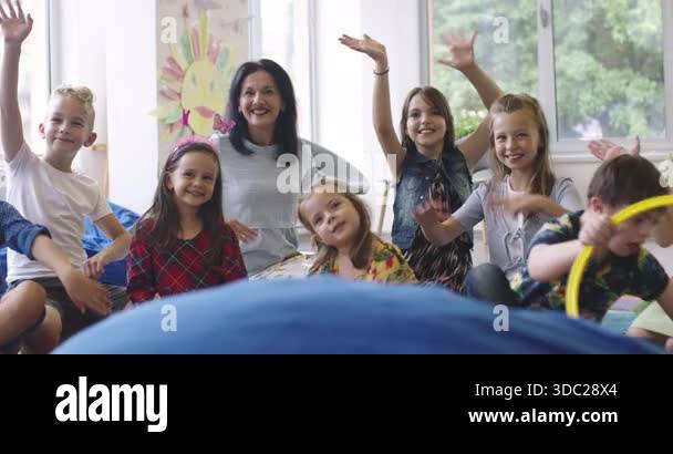 Happy diverse group of elementary children and a teacher sitting in a ...