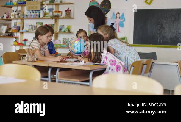 Teacher and elementary students learning geography with globe in ...