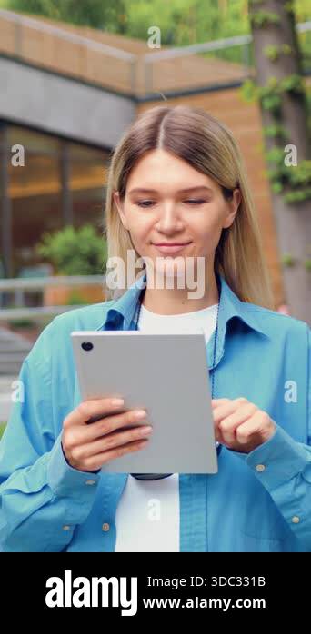 Happy businesswoman looking at tablet screen and chatting online while ...