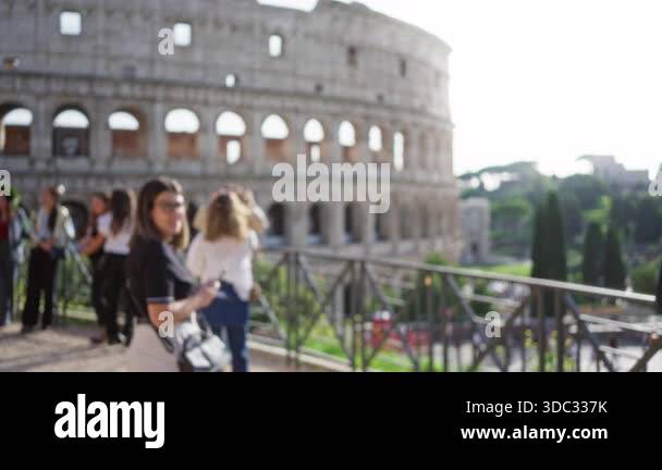 People gather at the colosseum in rome, italy, with blurred figures ...
