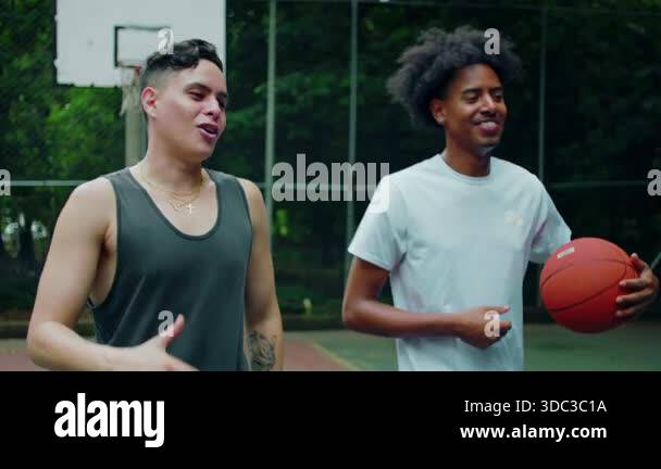 Two friends arriving at outdoor basketball court and greeting group of ...