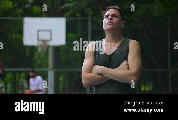 Latin Hispanic man standing on outdoor basketball court, arms crossed ...