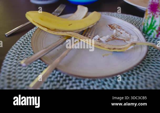 Banana skins rest on a plate with crumbs and utensils, capturing the ...