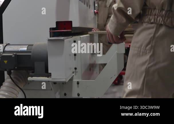 Worker takes wooden part with edge from industrial machine. Close-up of ...