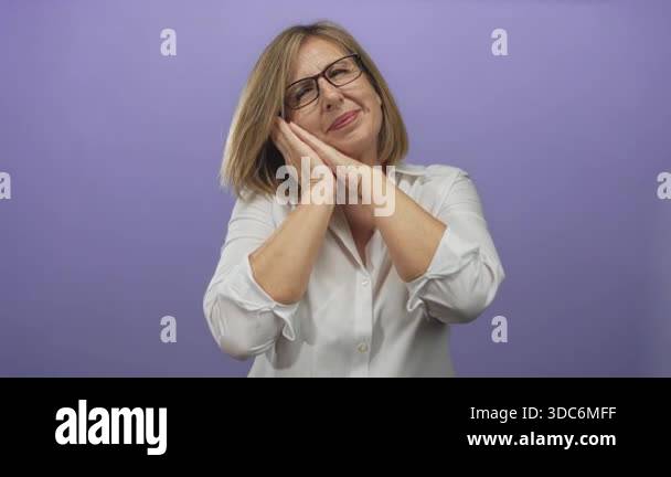Woman folds hands under cheek gesture in studio with purple backdrop ...