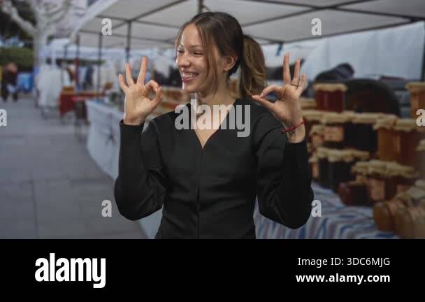 Woman showing ok sign with both hands at street market stall selling ...