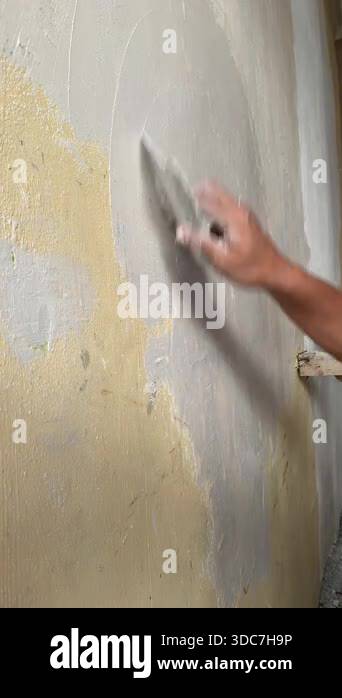 Close-up 4K of a construction worker hand applying wall compound with a ...
