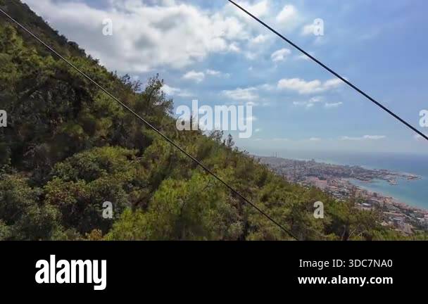 Cable car traveling over a forested hillside with a blue sky. Lebanon ...