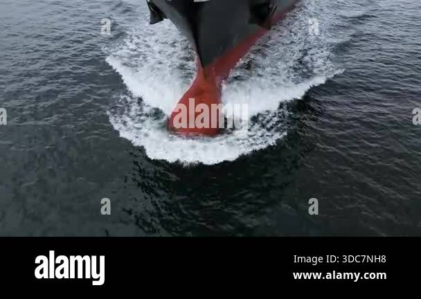 Aerial close-up view of a large cargo ship cutting through the sea ...