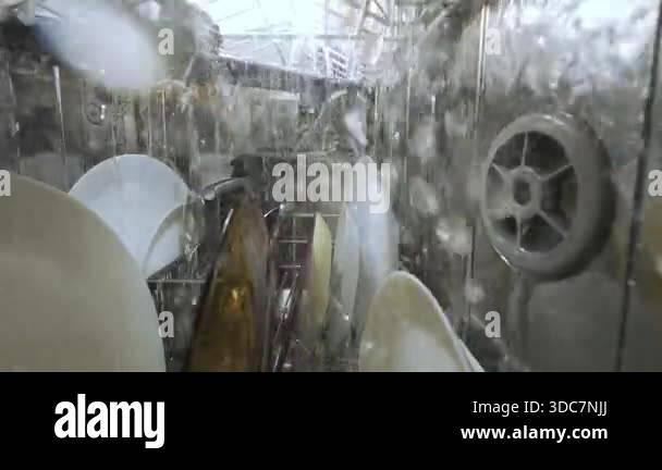 Slow-motion inside view of a running dishwasher with water splashing ...