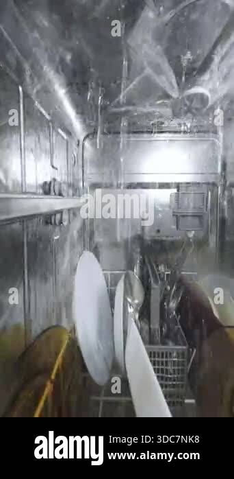 Inside view of a running dishwasher as water sprays over dishes then a ...