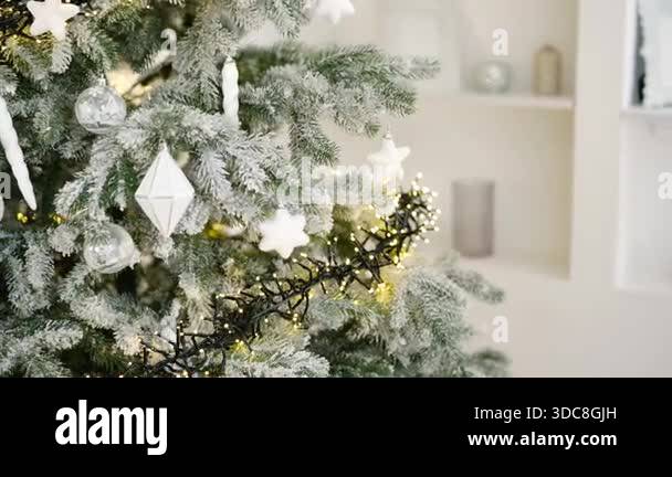 Decorated evergreen tree with white ornaments and fairy lights indoors ...