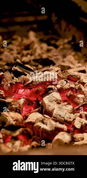 Bright red glowing embers with charred wood pieces and hot ash in a ...