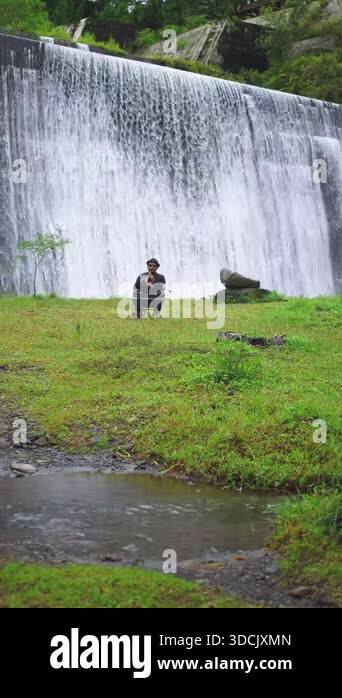 A musician plays his instrument on a sabo dam surrounded by grass. A ...