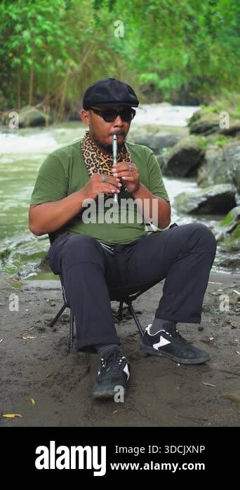 A male musician plays a wind instrument called a tin whistle against ...