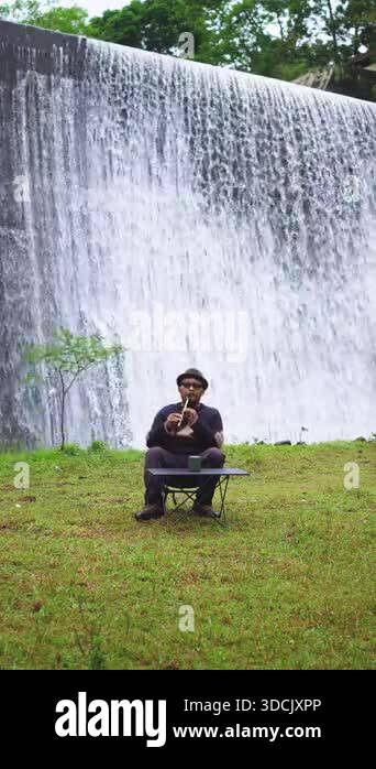 A musician plays his instrument on a sabo dam surrounded by grass. A ...