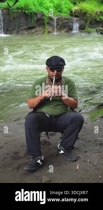 A male musician plays a wind instrument called a tin whistle against ...