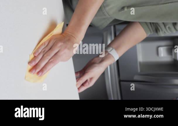 A person is cleaning the kitchen countertop in a modern kitchen. The ...
