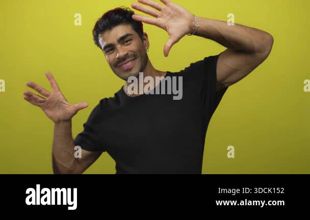 Man framing scene with hands and smiling face in yellow studio with ...