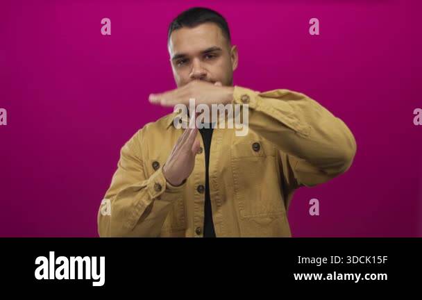 Young hispanic man wearing tan jacket makes time out gesture in studio ...
